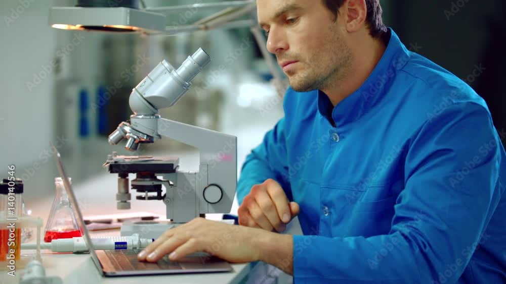 Male scientist looking microscope in lab. Lab man using scientist ...