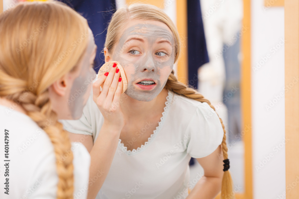 Woman removing mud facial mask with sponge Stock-Foto | Adobe Stock