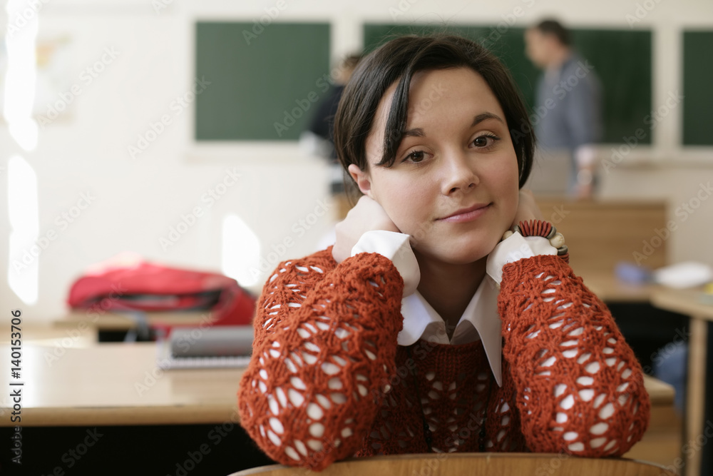 Foto de Teenage girl sitting on a chair, arms leaning on back do Stock | Adobe Stock