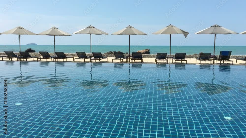 Umbrella and swimming pool in hotel resort with sea beach background ...