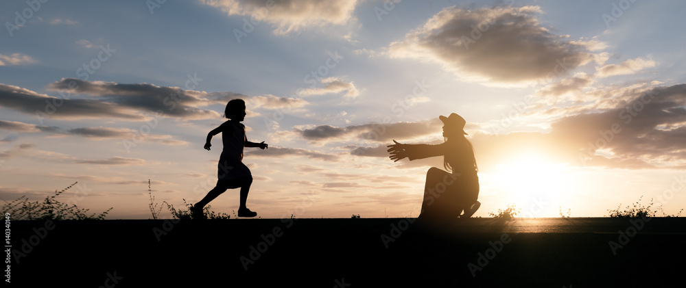 a silhouette of a happy girl child running into the arms of his loving ...