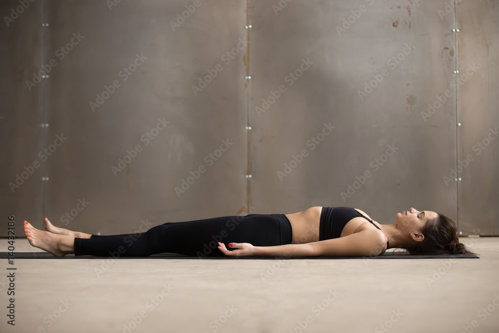 Young attractive woman practicing yoga, lying in Dead Body, Savasana ...