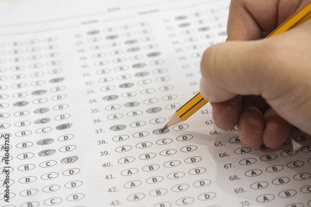 A pencil sitting on a test bubble sheet and alarm clock, optical form ...