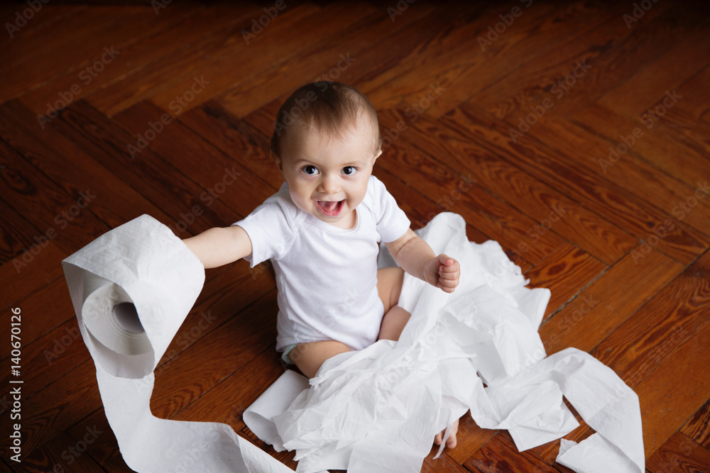 happy baby playing with toilet paper on the living room wooden floor ...