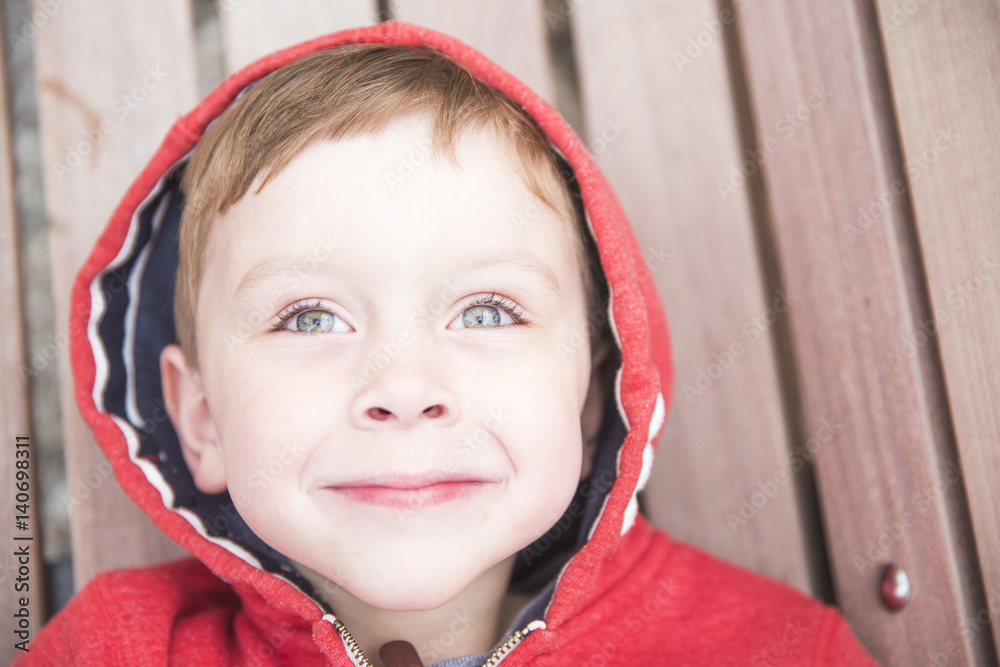 Happy boy smiling and looking at the sky. The child in the hood lies on ...