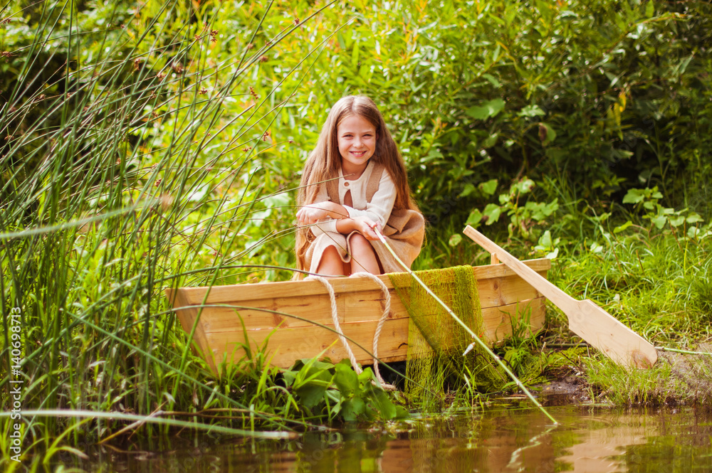 Cute little girl having fun in a boat by a river Stock Photo | Adobe Stock