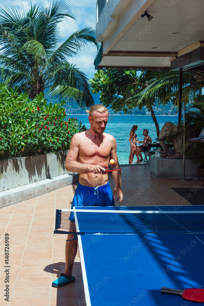 Man playing ping pong. Vertical outdoors shot of shirtless man playing ...