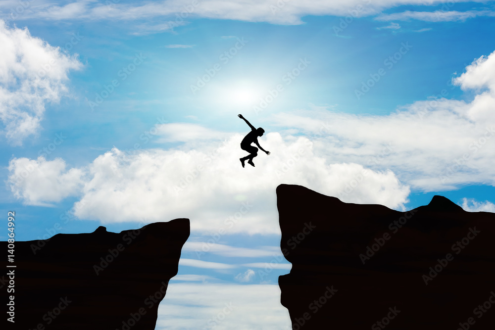 Man jump through the gap between hill.man jumping over cliff on sunset ...