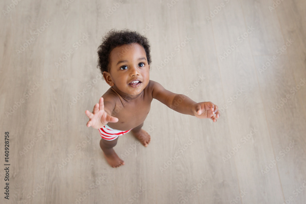 child standing on a wood floor looking up with arms extended Stock ...