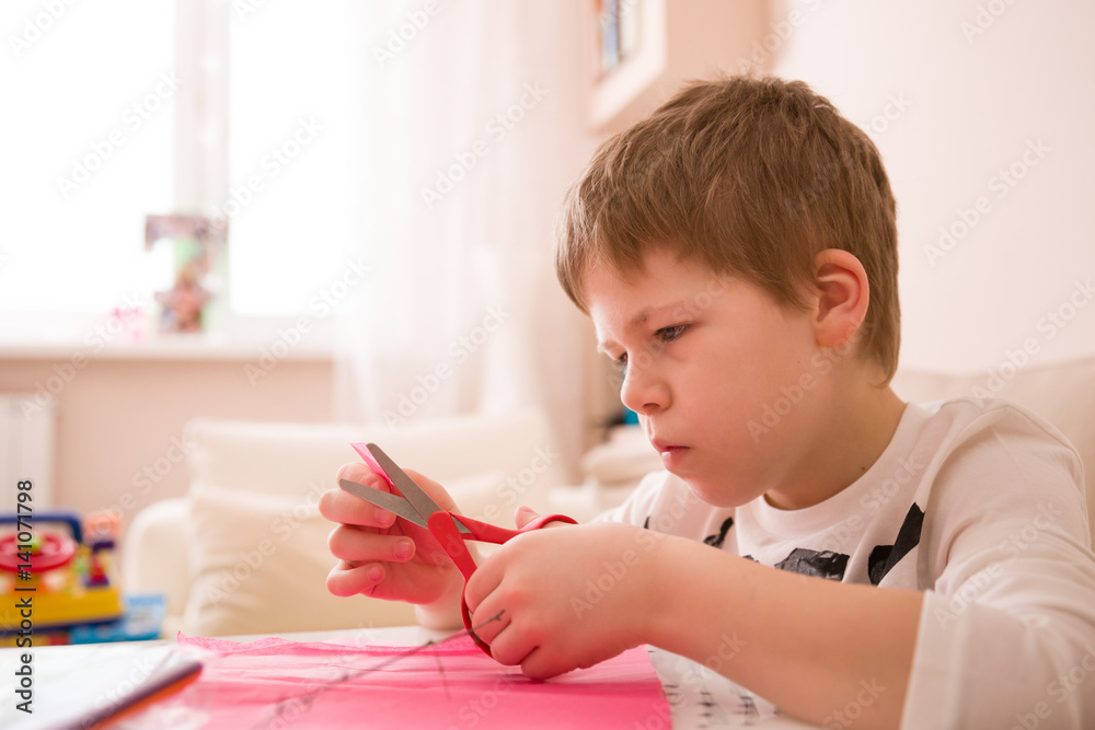 Cute kid boy crafting with scissors and color paper at his desk. Hobby ...