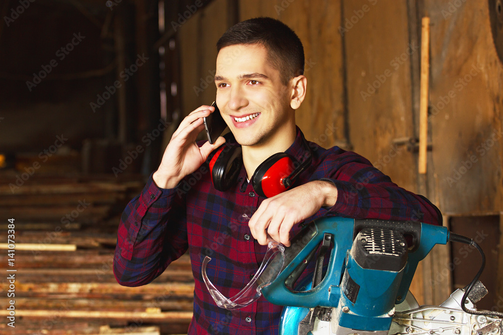Smiling workman dressed in the checkered shirt talking the phone near ...
