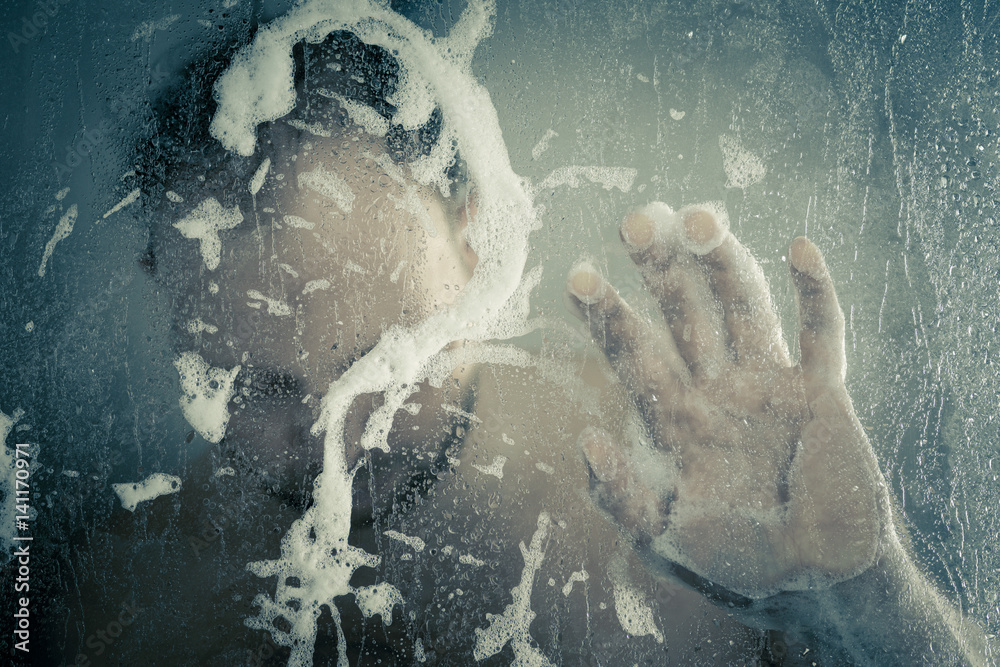 stressed man taking a shower standing under flowing water and draws a ...