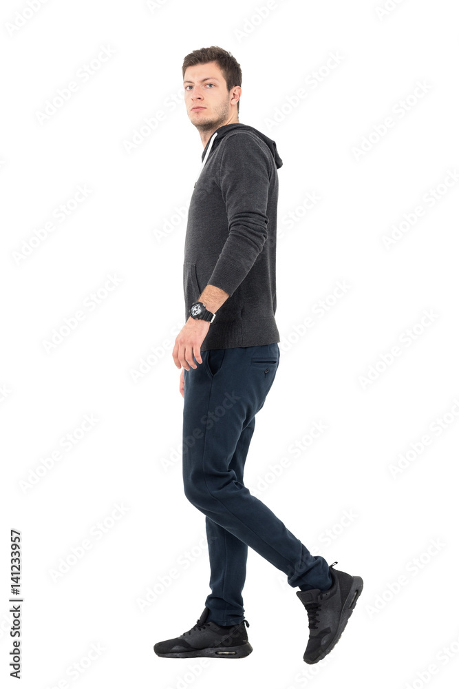 Side view of young man in sportswear walking and looking at camera ...
