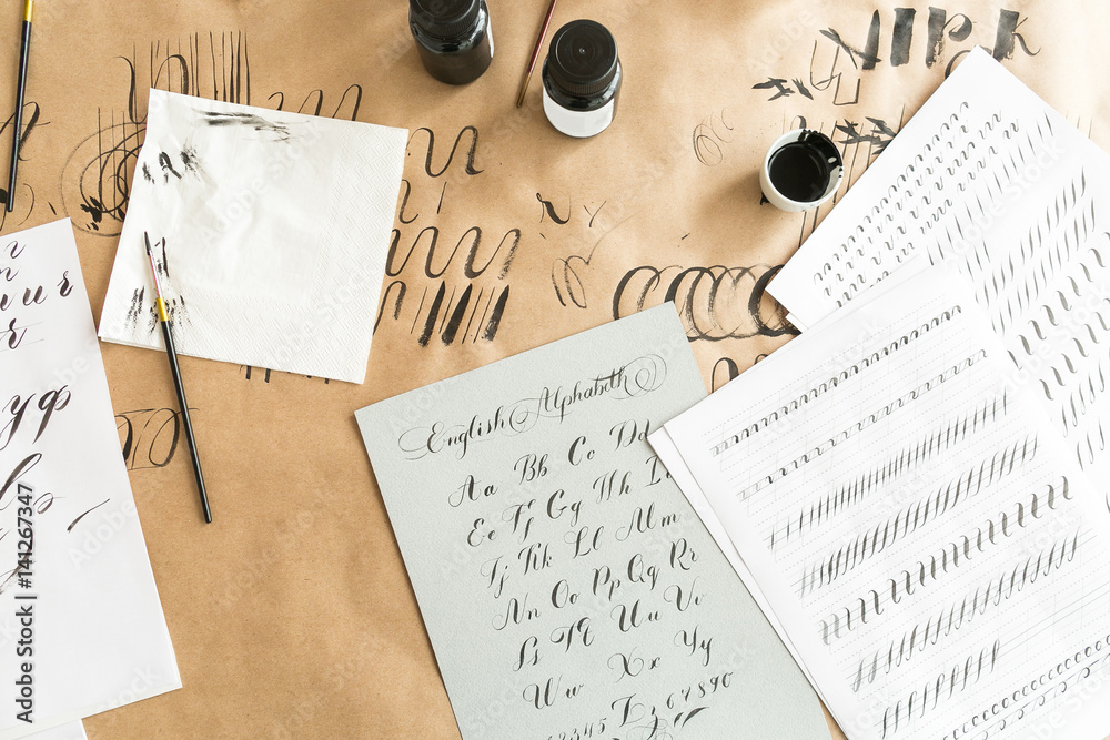 Calligraphy sheets, nibs, paper, ink and pens on a kraft background ...