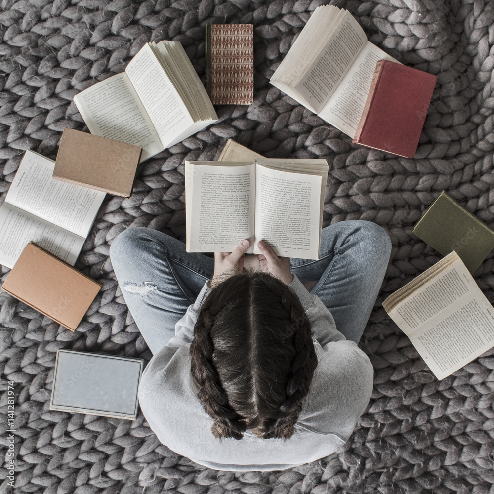 Woman sitting crossed legged reading lots of books Stock Photo | Adobe ...