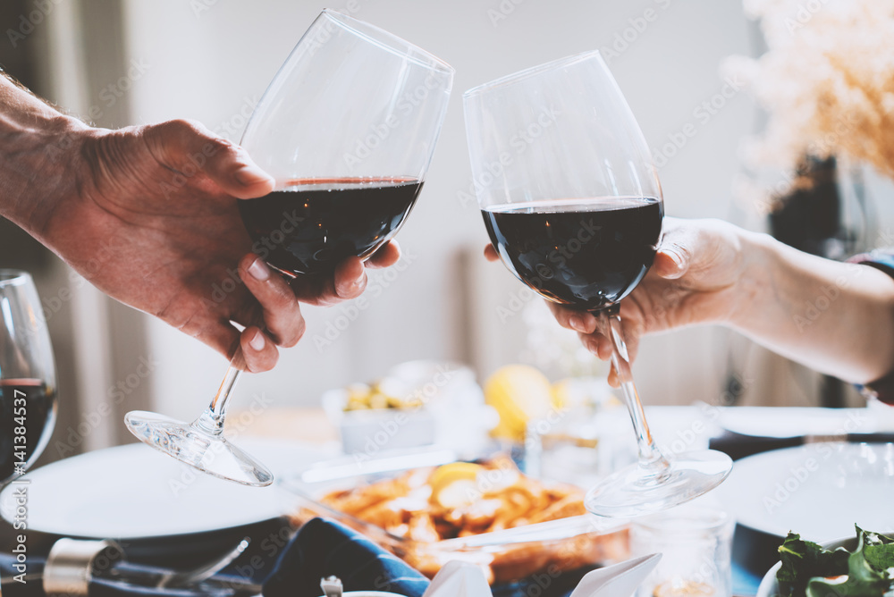 Happy romantic couple cheering with glasses of red wine at restaurant ...