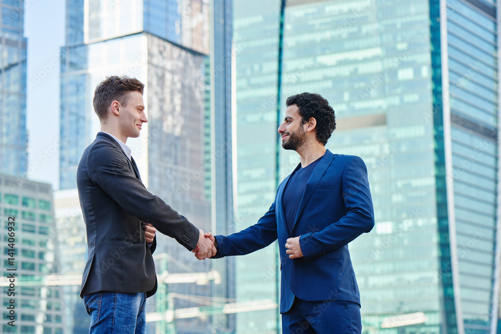 Men in suits shake hands with each other on the background of ...