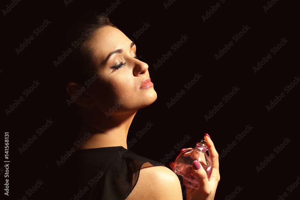 Beautiful young woman with bottle of perfume on dark background Stock ...