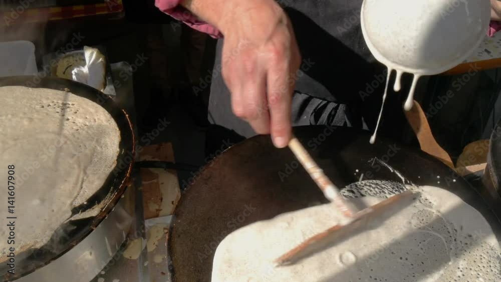 4K close up of a man spreading crepe batter a crepe, or buckwheat ...