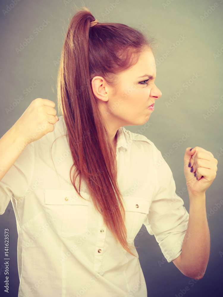 Angry mad woman clenching fist punching on gray. Stock Photo | Adobe Stock