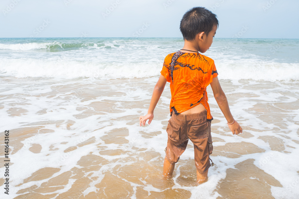 boy playing on the beach in the water Stock Photo | Adobe Stock
