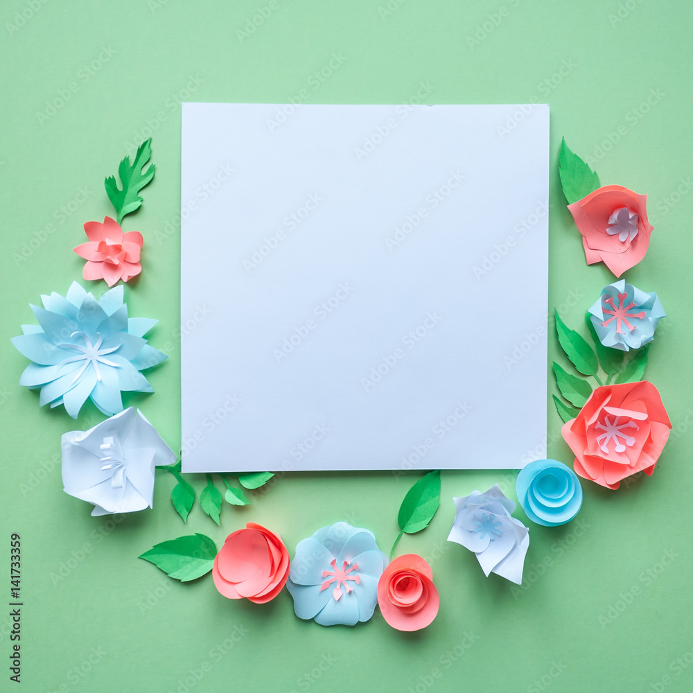 square frame with color paper flowers on the green background. Flat lay ...