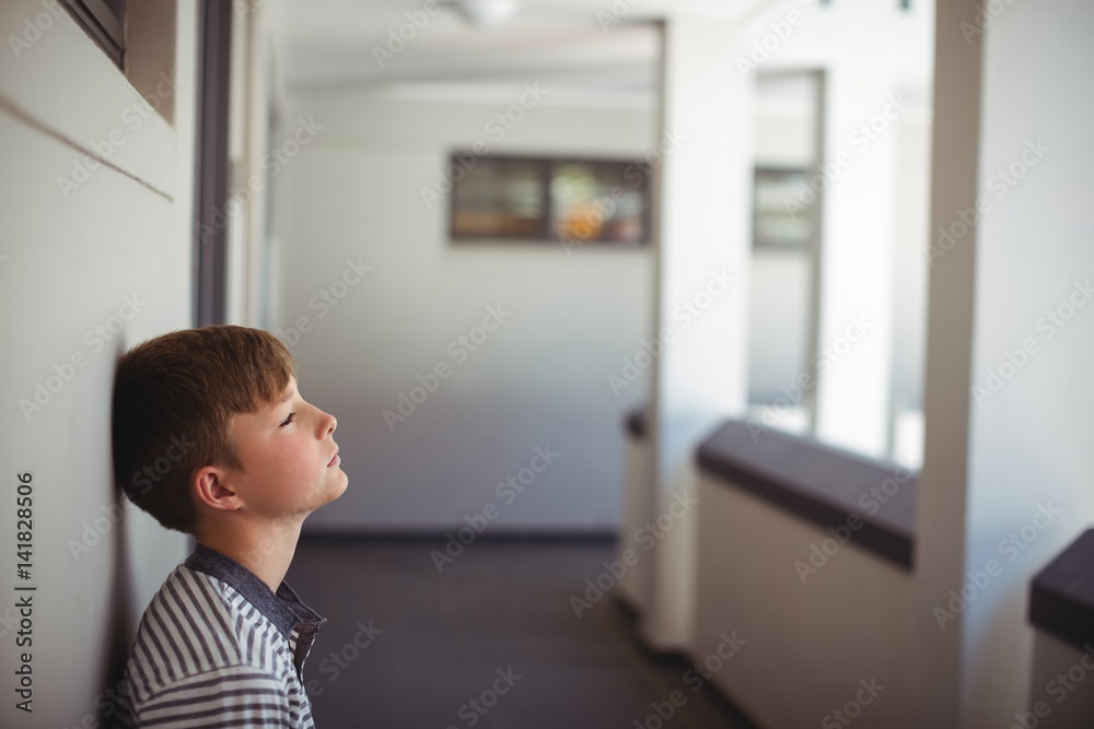 Sad schoolboy leaning head against wall in corridor Stock Photo | Adobe ...