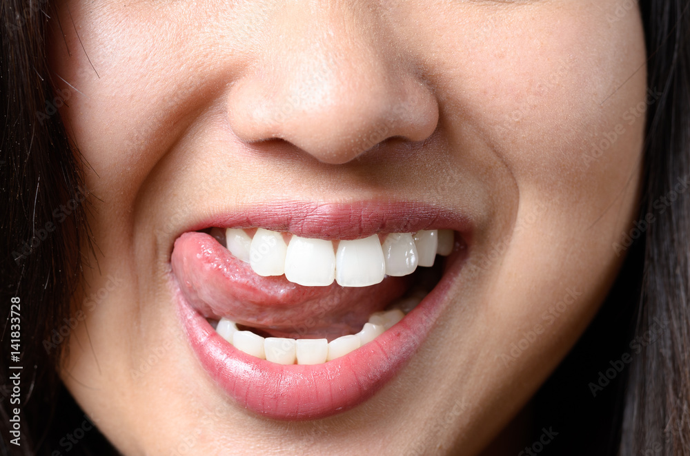 Sensual young woman licking her teeth foto de Stock | Adobe Stock