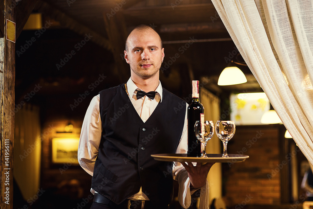 The waiter offers visitors wine,Waiter in uniform waiting an order ...