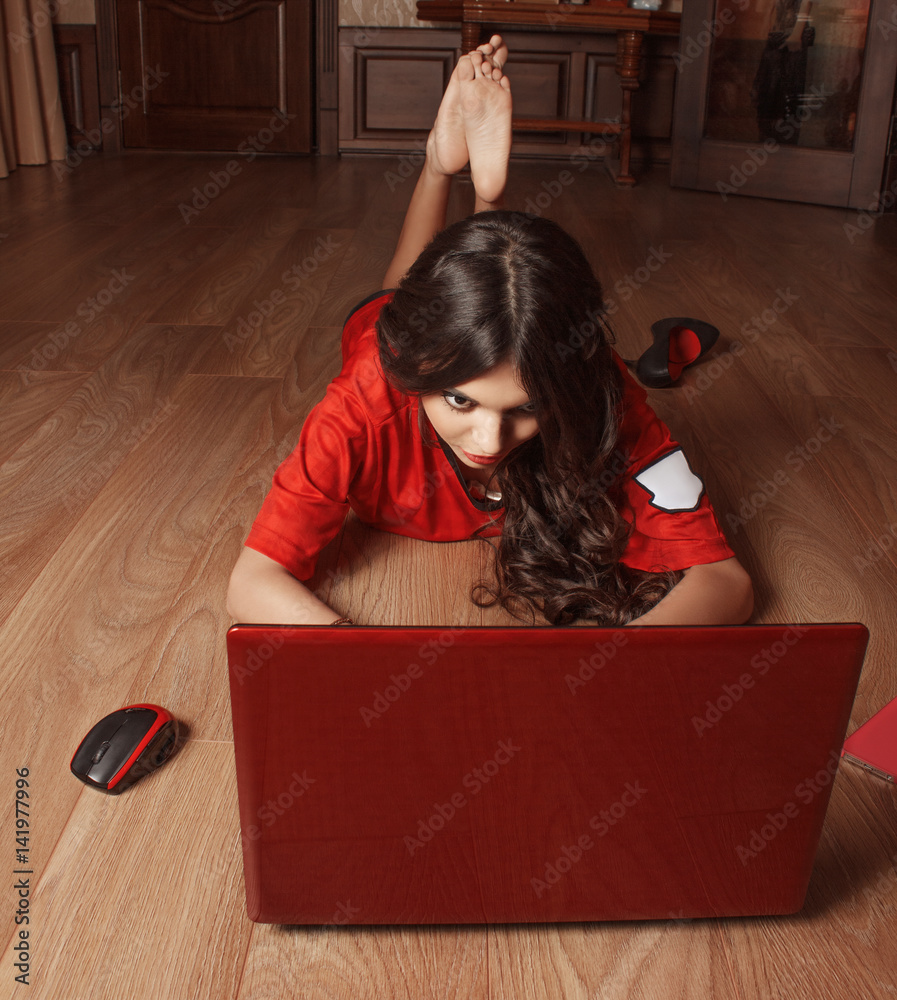 Foto de Young girl in red shirt lying on the floor and works over a ...
