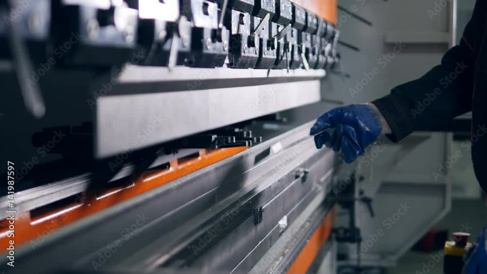 Worker bend metal sheet on a modern bending industrial machine at a ...