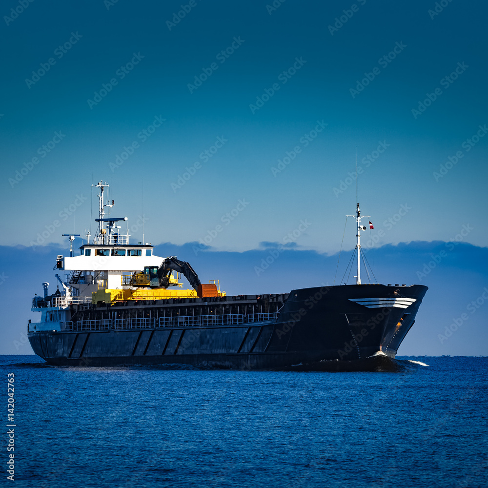 Black cargo ship with long reach excavator moving by baltic sea Stock ...
