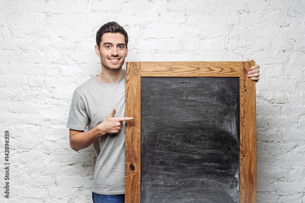 Attractive young man pointing at blackboard. Handsome male standing ...