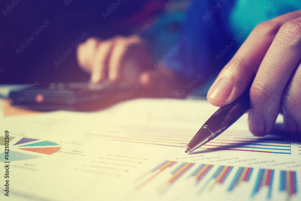 Woman hand holding pen pointing on summary report chart and doing ...