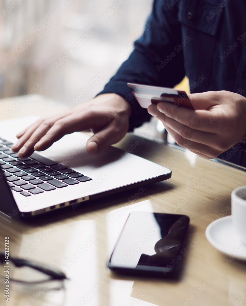 Businessman holding plastic credit card in hand and using laptop ...