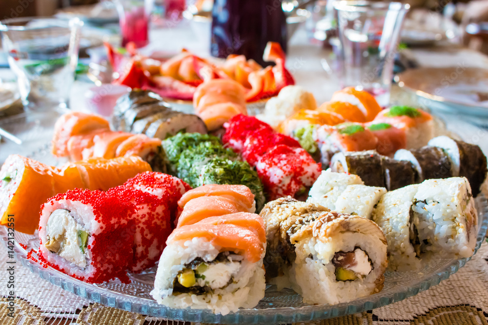 Big roll sushi set on a large plate at home. Stock Photo | Adobe Stock