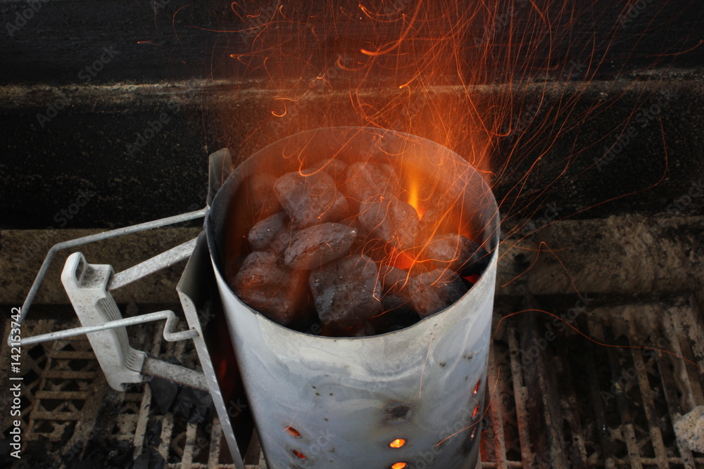 BBQ chimney starter with flames and spark trails Stock Photo | Adobe Stock