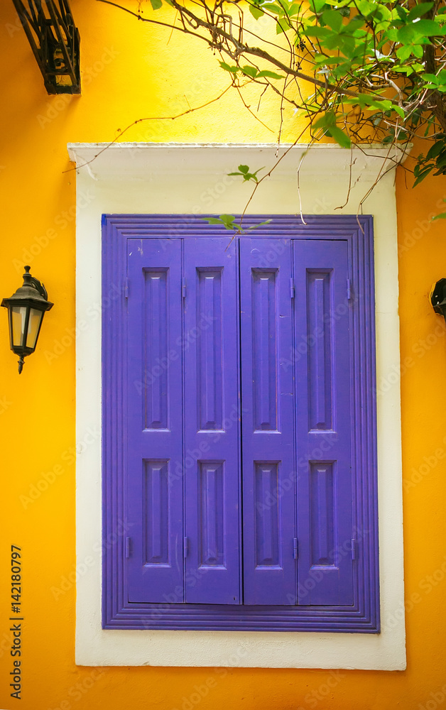 Purple window shutters on a yellow wall Stock Photo | Adobe Stock