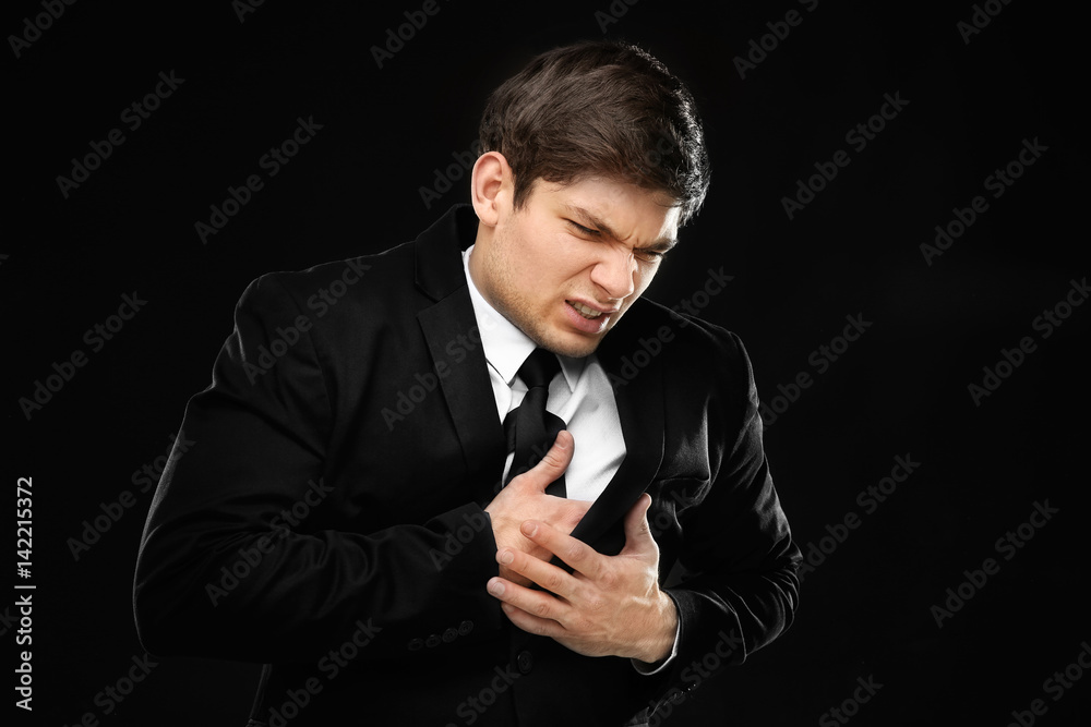 Heart attack concept. Young man suffering from chest pain on black ...