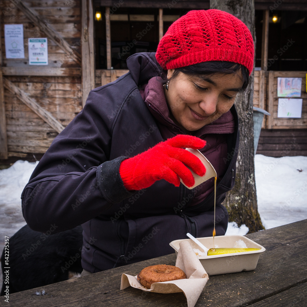 Foto de young smiling woman pouring warm maple syrup on snow creating a ...