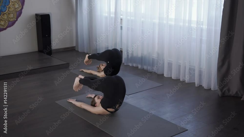 Women who practice yoga tilt their legs behind their heads, and hands ...