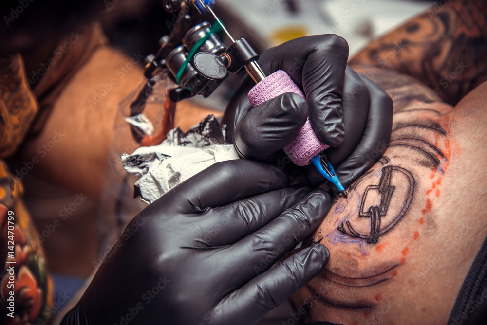 Professional tattoo artist showing process of making a tattoo in tattoo ...