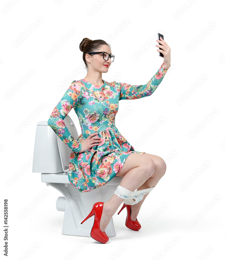 Young woman in dress sits on the toilet and makes a selfie on a ...