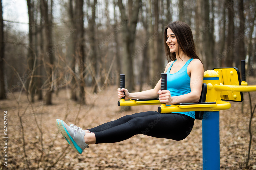 Portrait of strong young woman hanging on wall bars with her legs up ...