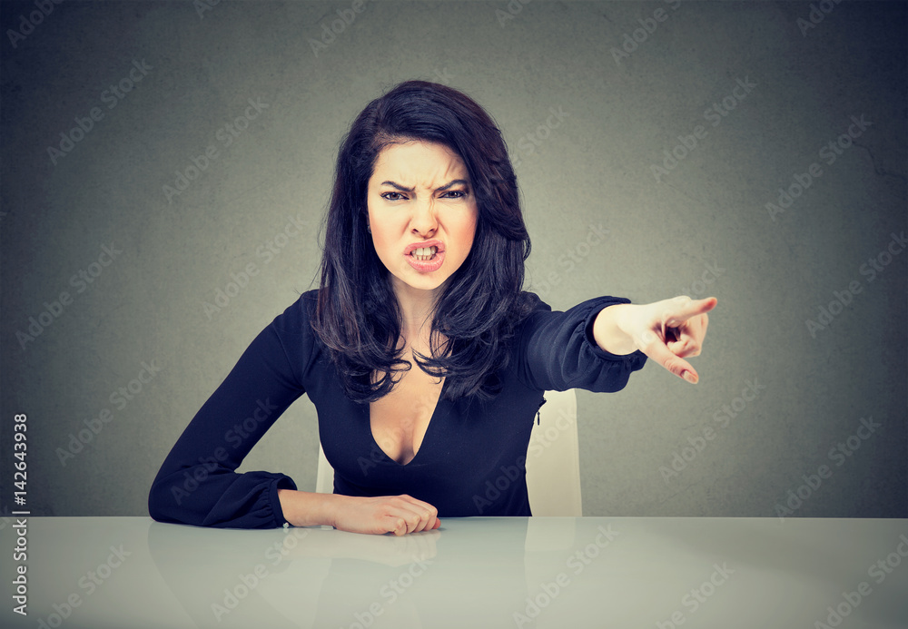 Angry business woman sitting at her desk and screaming pointing with ...