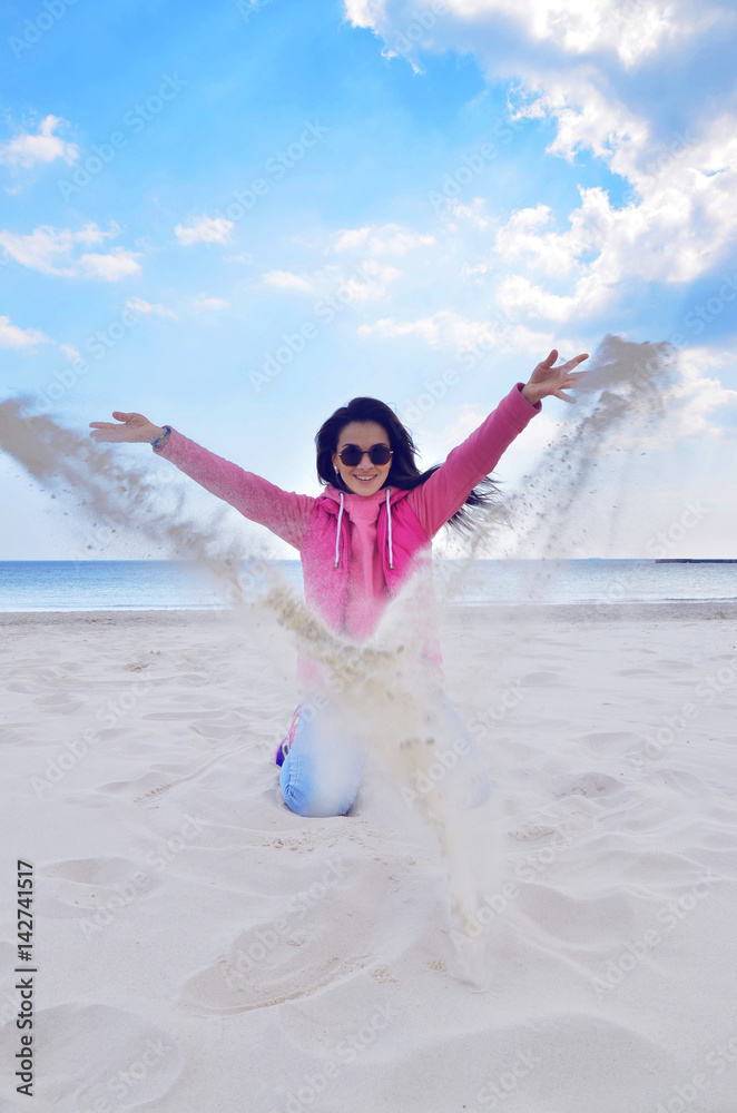 Young girl on the beach throwing sand, running and smiling. Happy girl ...