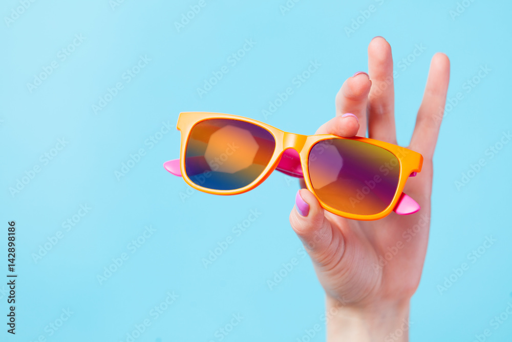 photo of female hand holding sunglasses on the wonderful blue ...