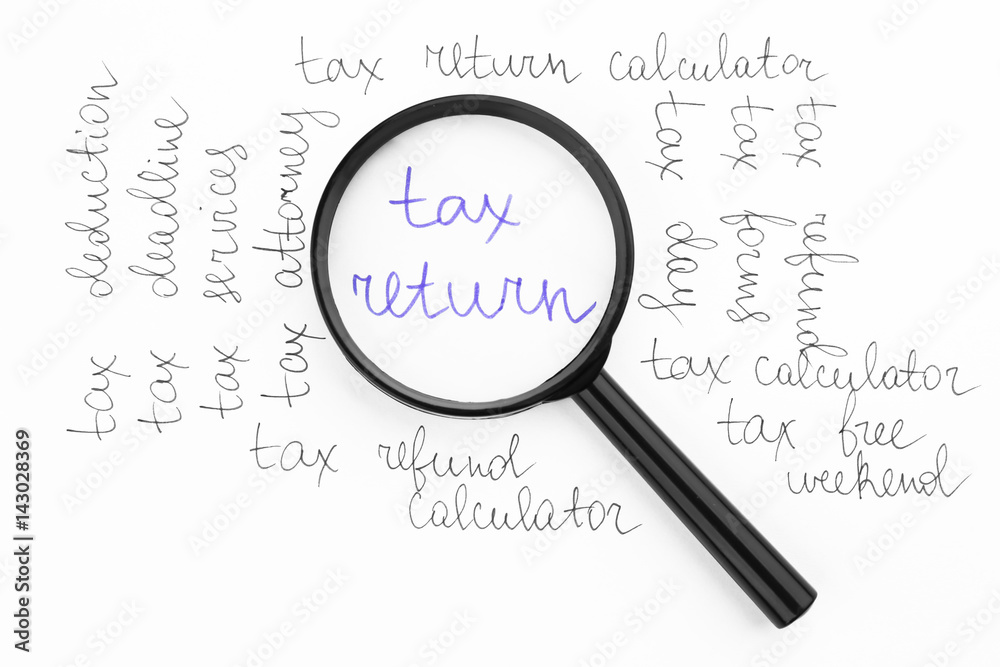 TAX RETURN text written on paper and hand glass Stock Photo | Adobe Stock