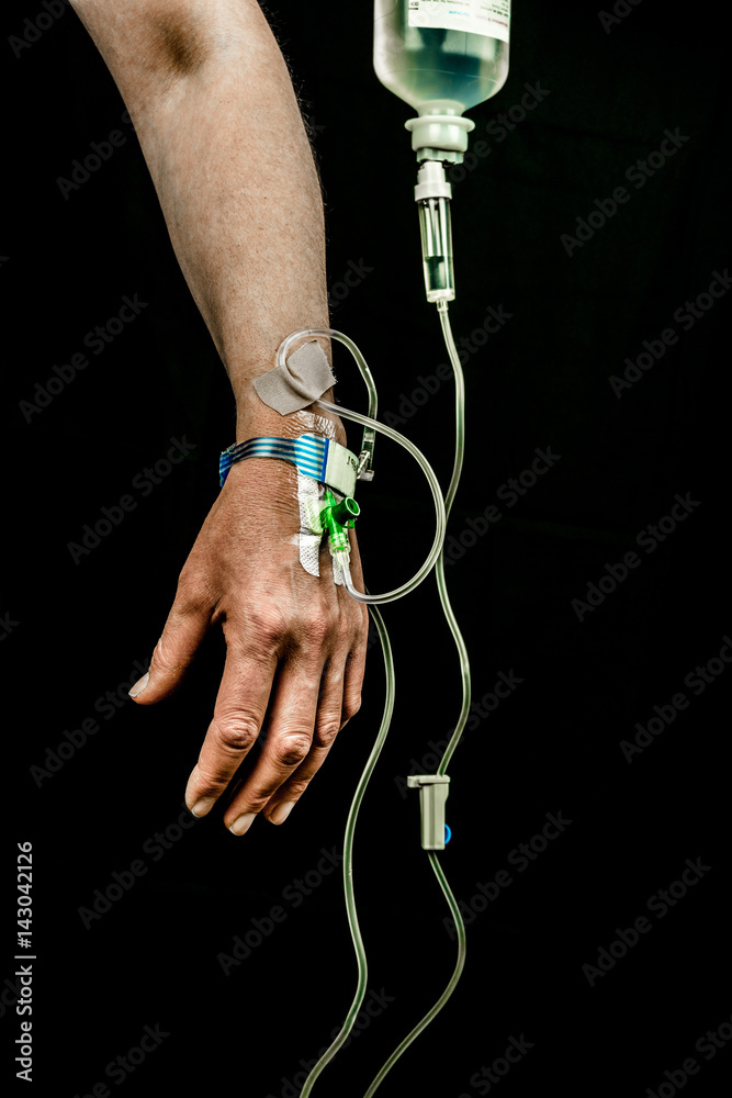 Hand and arm of patient with iv fluid treatment on black background ...