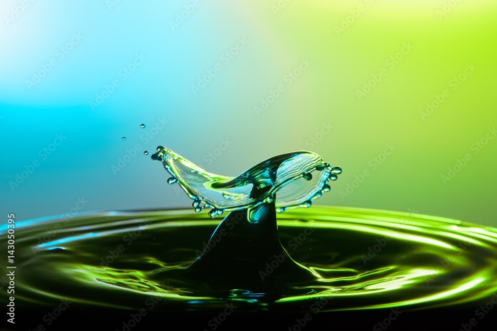 Water drop collision close up image with a green and blue background ...